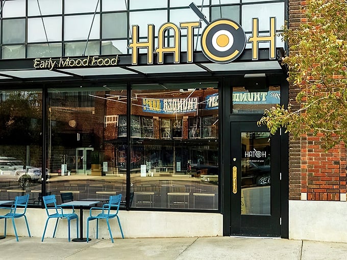 The golden glow of Hatch's signage beckons like a breakfast lighthouse. Those blue chairs aren't just seating&mdash;they're your front-row tickets to the morning's main event.