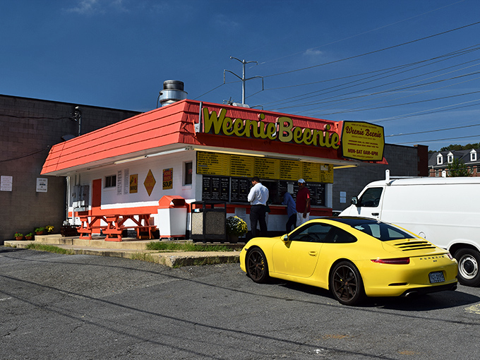 The iconic pink-and-yellow Weenie Beenie stands proudly against a blue Virginia sky, like a time capsule of American roadside charm waiting to be discovered.