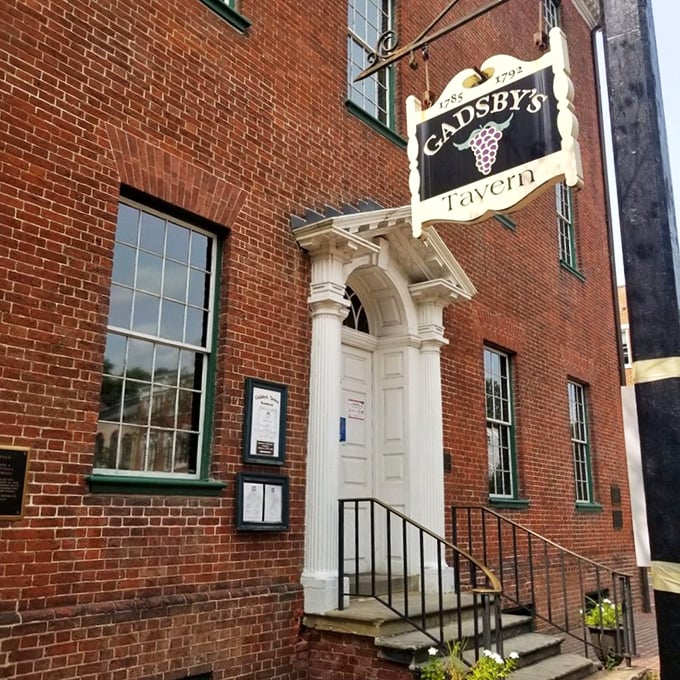 The historic fa&ccedil;ade of Gadsby's Tavern beckons with its colonial charm. That hanging wooden sign has been welcoming hungry patriots since 1785.