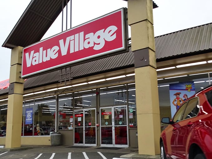 The iconic red Value Village sign beckons like a lighthouse for treasure hunters navigating the sea of suburban retail. Welcome to thrift paradise!
