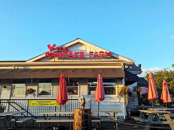 The iconic red Pancake Farm sign beckons hungry travelers like a breakfast lighthouse. Those picnic tables aren't just seating&mdash;they're the waiting room for pancake paradise.