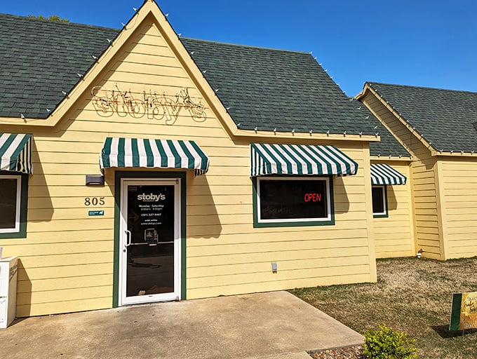 The cheerful yellow exterior of Stoby's with its iconic striped awnings stands like a beacon of comfort food promise in Conway.