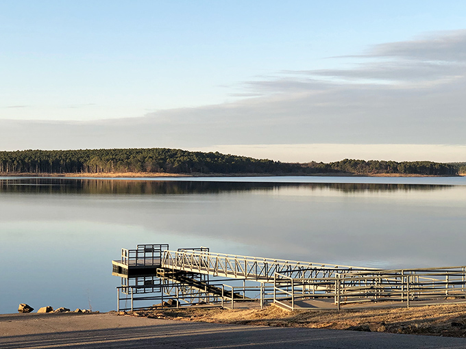 Mirror-like waters reflect the forested shoreline at McGee Creek Reservoir, where silence is only broken by the occasional splash of a jumping bass.