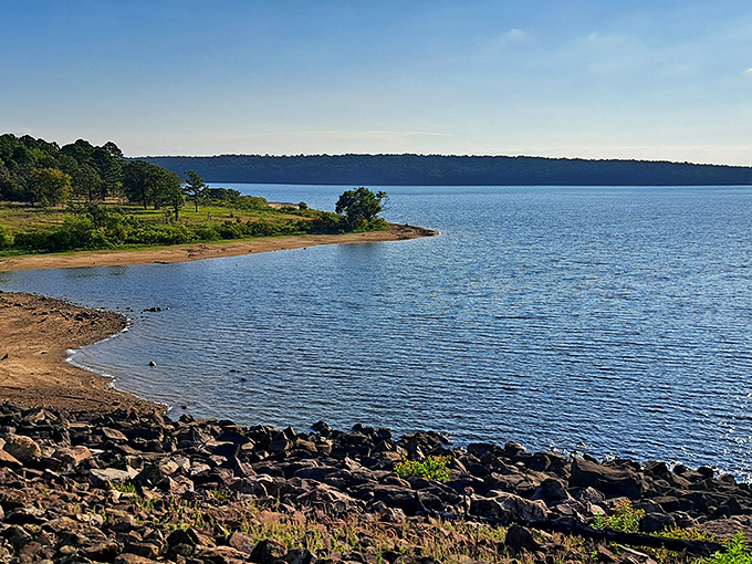 Mirror-like waters reflect the forested shoreline at McGee Creek Reservoir, where silence is only broken by the occasional splash of a jumping bass.