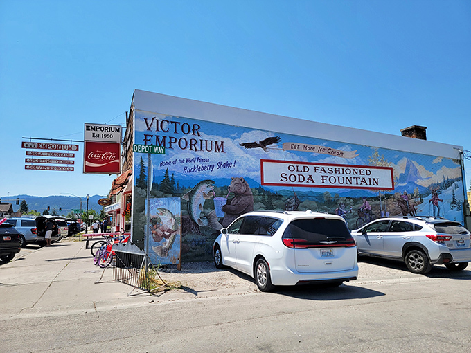 The mural-adorned exterior of Victor Emporium stands like a portal to simpler times, beckoning travelers with promises of icy purple perfection beneath Teton skies.