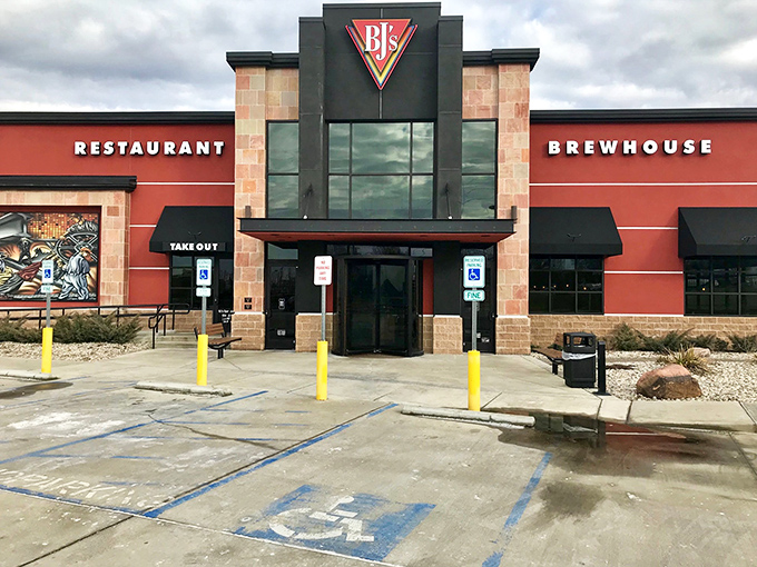 The bold red exterior of BJ's stands like a beacon for hungry travelers, promising craft brews and comfort food within those stone-accented walls.