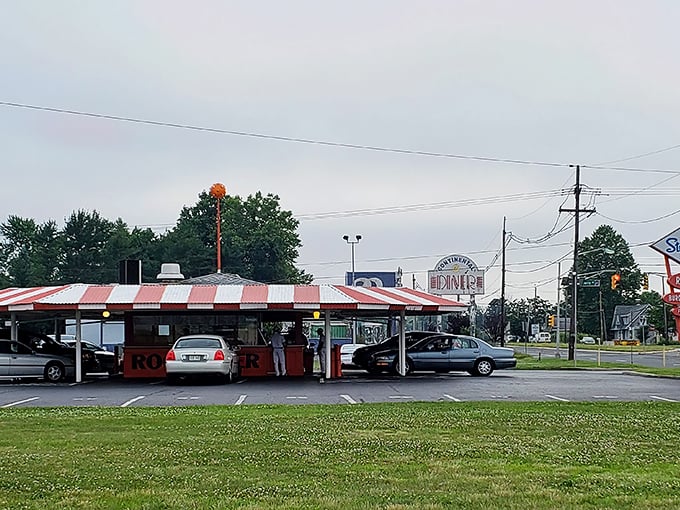 The iconic red and white striped canopy of Stewart's Drive-In stands like a time capsule on wheels, beckoning hungry travelers with promises of nostalgia and root beer.