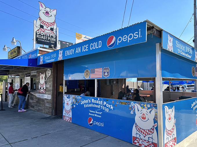 The iconic blue exterior with its cheerful pig mascot stands as a beacon of sandwich excellence in South Philly's industrial landscape.