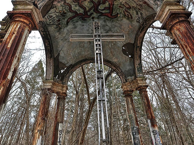 The haunting centerpiece of Hell House: a metal cross stands sentinel within weathered columns, like a scene from a gothic novel come to life.