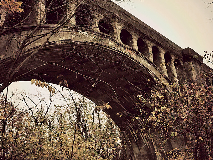 The weathered arches of Avon's Haunted Bridge stand sentinel against an autumn sky, where concrete and legend have intertwined for generations.