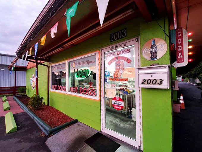 The lime-green beacon of Willy-Yums stands out like a culinary lighthouse, complete with festive pennant flags and enough "HOT DOG" signs to leave zero doubt about what's cooking inside.