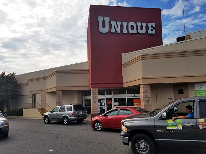 The iconic red facade of Unique Thrift Store stands like a beacon of bargain possibilities in Falls Church, promising treasures within those sliding glass doors.