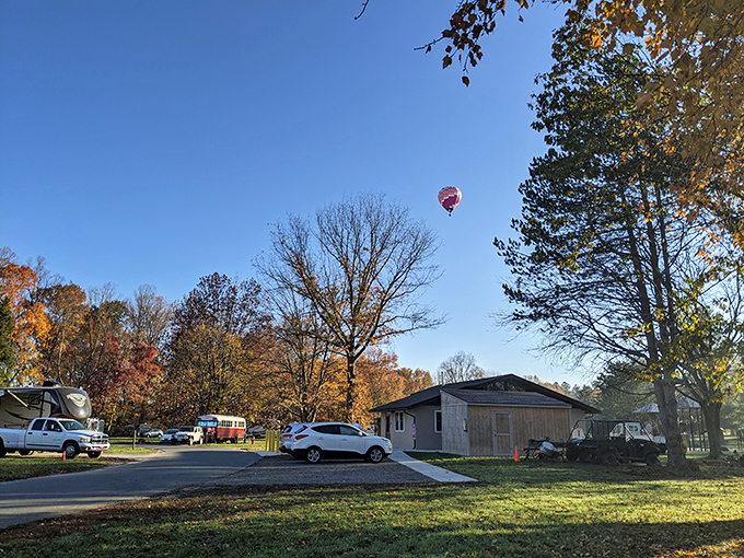 Fall magic at its finest! A hot air balloon drifts over Lums Pond campground, where autumn trees create nature's most spectacular color palette.