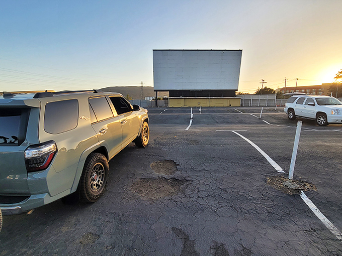 The magic hour at Sunset Drive-In, where cars gather like faithful pilgrims to worship at the altar of cinema under the twilight sky.