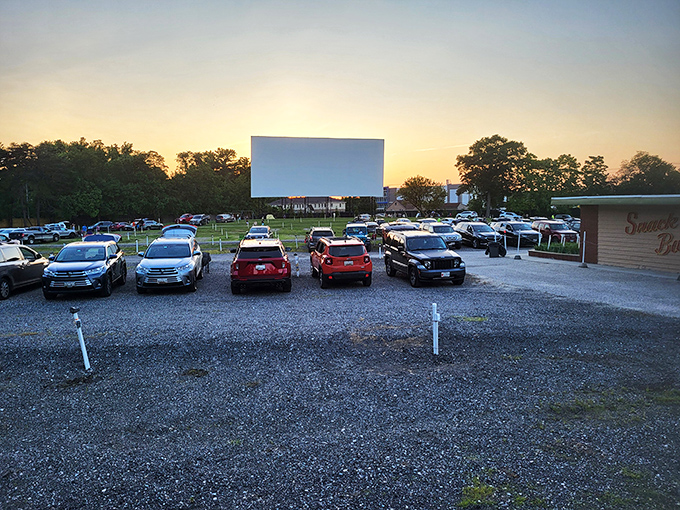Twilight magic unfolds as families gather beneath Bengies' massive screen, where the "Good Evening Folks" welcome glows against a Maryland sunset.