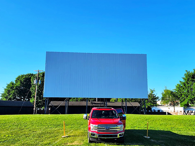 Twilight magic unfolds as cars line up facing the massive white screen, nature providing the perfect backdrop for cinematic adventures.