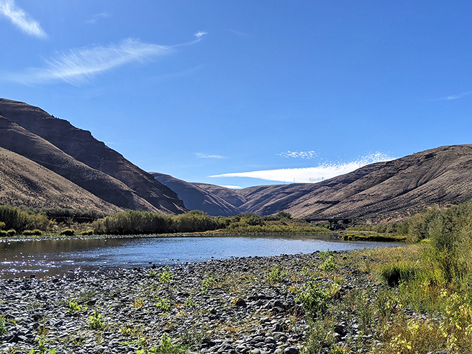 The John Day River mirrors the rugged canyon walls like nature's own infinity pool, creating a moment of perfect symmetry in Oregon's high desert wilderness. 
