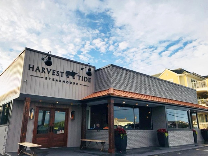 The coastal charm of Harvest Tide's exterior belies the culinary magic happening inside. Gray siding, brick accents, and wooden beams create an inviting first impression.