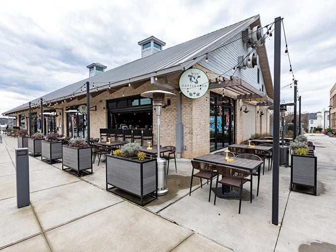 Modern farmhouse meets culinary playground at Cattle Shed's inviting exterior. String lights and comfortable outdoor seating promise evenings of beef-centric bliss in Alpharetta.