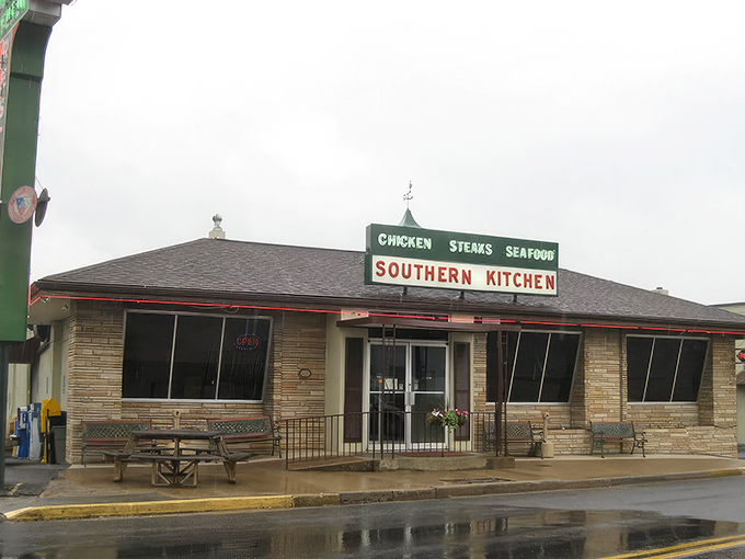 The stone facade of Southern Kitchen stands proudly in New Market, where that green sign has been beckoning hungry travelers for generations. American flags flutter in the mountain breeze, promising patriotic portions inside.