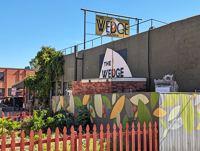 The Wedge's exterior is like a colorful storybook come to life. That vibrant orange fence and playful mural practically scream "good times and great pizza await inside!"