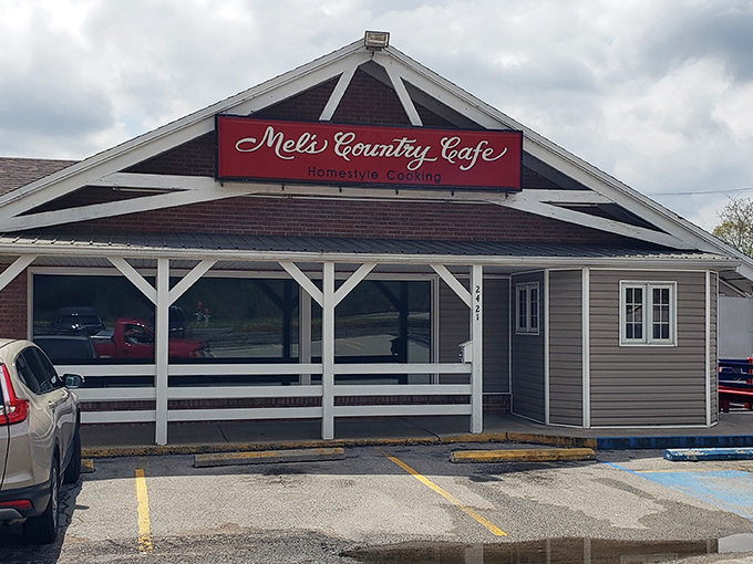 The unassuming exterior of Mel's Country Cafe sits like a red-signed promise of comfort food bliss under Missouri skies. 