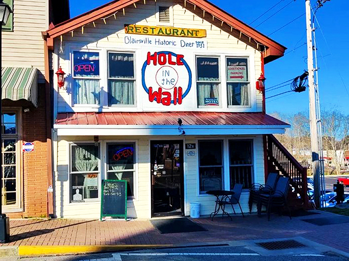 The iconic facade of Hole in the Wall beckons hungry travelers with its charming hand-painted sign and string lights&mdash;a North Georgia breakfast beacon worth the drive.