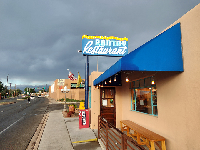 The iconic blue Pantry sign stands like a beacon of breakfast hope against the New Mexico sky, promising culinary salvation to hungry souls below.