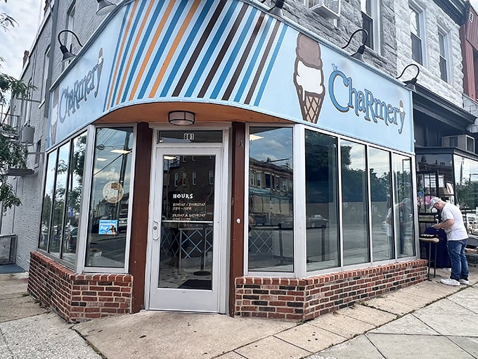 The corner shop that launched a thousand cravings. The Charmery's blue-striped awning and iconic ice cream cone logo beckon from Hampden's bustling Avenue.