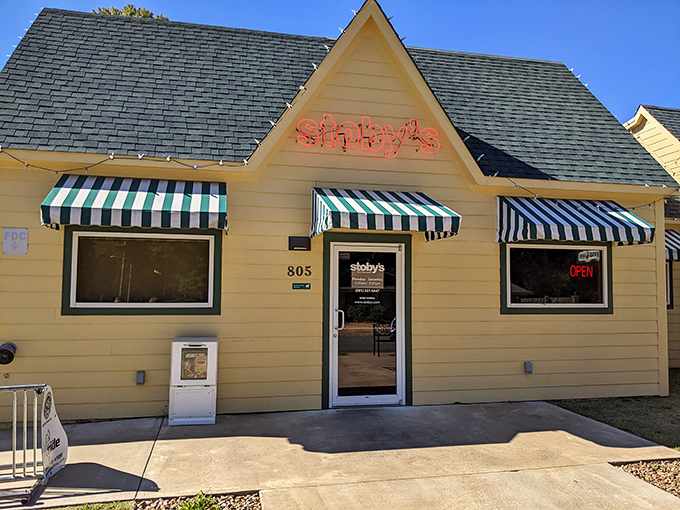 The cheerful yellow exterior of Stoby's with its iconic striped awnings stands like a beacon of comfort food promise in Conway.
