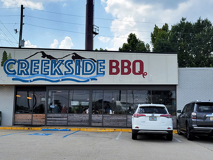 The blue and red Creekside BBQ sign beckons like a lighthouse for the hungry, promising smoky treasures inside this Pelham landmark. 