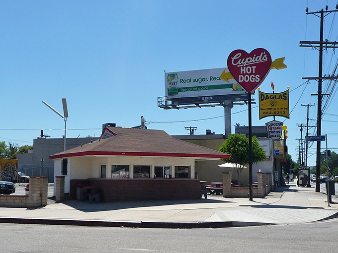 The iconic heart-shaped sign beckons hungry travelers like a culinary lighthouse. Cupid's modest exterior hides world-class hot dog magic within.