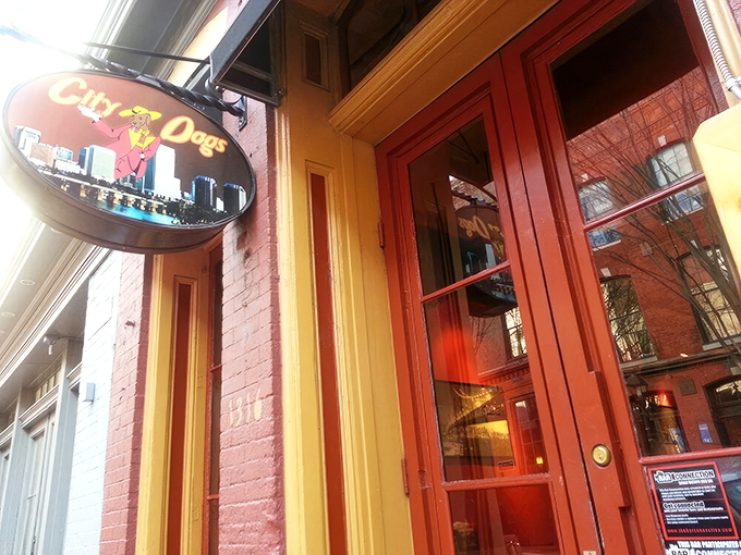 The cheerful red brick and bright yellow awning of City Dogs beckons hungry passersby like a lighthouse for the gastronomically adrift.