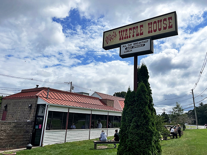 The iconic Vic's Waffle House sign stands tall against the Massachusetts sky, beckoning hungry travelers with promises of breakfast bliss and maple-drenched dreams. 