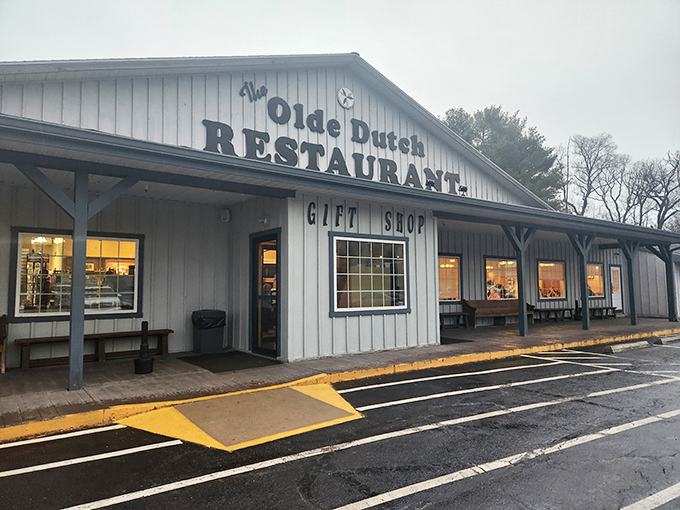 Welcome to comfort food paradise! The blue-sided exterior of Olde Dutch Restaurant in Logan invites hungry travelers with its charming porch and promise of home-cooked delights.