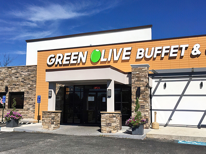 The golden-orange facade of Green Olive Buffet stands like a beacon to hungry travelers. Stone accents and modern signage promise culinary adventures within.