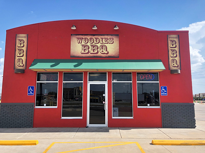 The bright red exterior of Woodies BBQ stands like a beacon for hungry travelers, promising smoky delights within those humble walls.