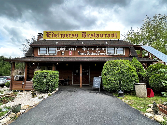 The rustic log cabin exterior of Edelweiss Restaurant promises Bavarian delights beneath stormy skies. Like finding a German postcard come to life in Virginia's Shenandoah Valley.