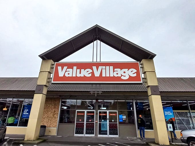 The iconic red Value Village sign beckons like a lighthouse for treasure hunters navigating the sea of suburban retail. Welcome to thrift paradise!