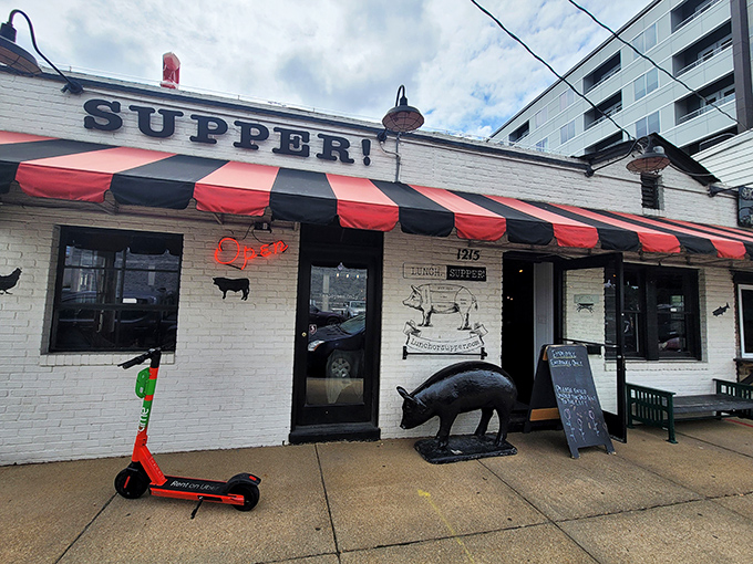 The iconic white brick exterior of LUNCH.SUPPER! with its jaunty red and black awning promises Southern comfort before you even step inside.