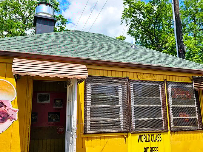The humble yellow shack with stacked firewood speaks volumes: real pit beef doesn't need fancy digs when the smoke does the talking.