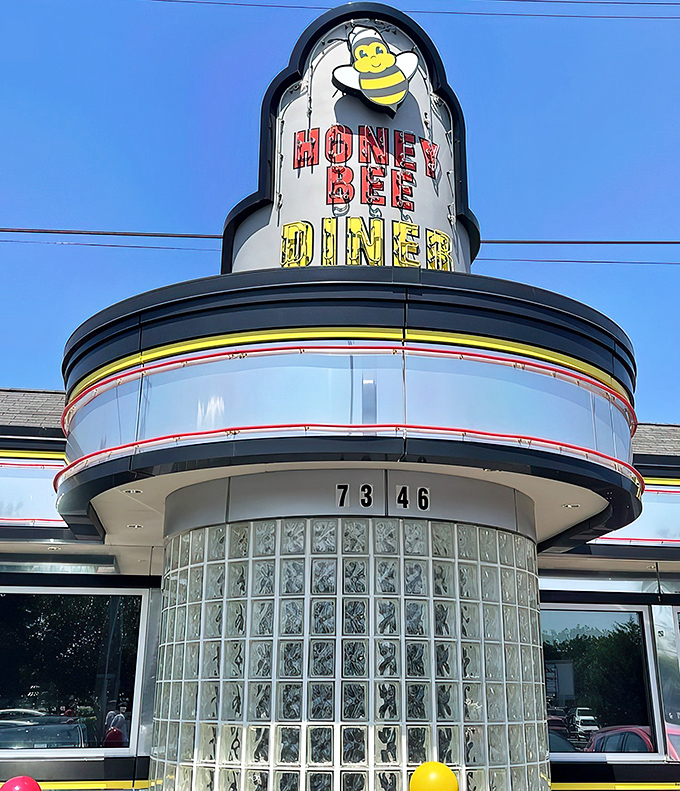 The classic mid-century diner silhouette of Honey Bee stands proud against the Maryland sky, its cheerful bee mascot promising sweet culinary delights within.