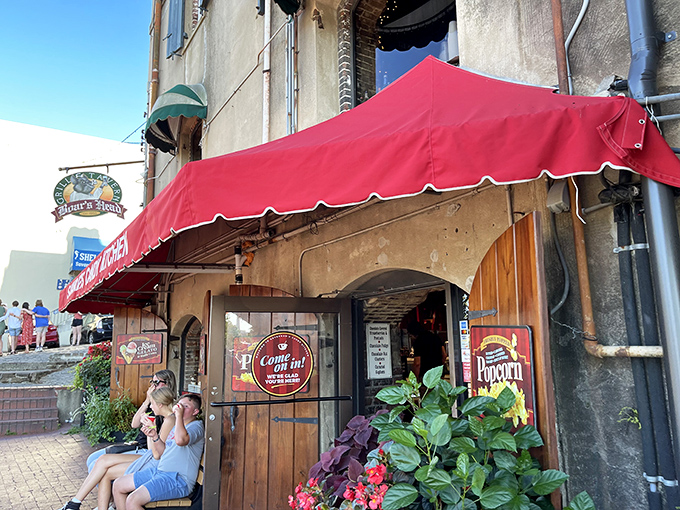 The iconic red awning of Savannah's Candy Kitchen beckons like a sweet siren call on River Street. Rustic wooden doors and lush planters create the perfect entrance to sugar paradise.