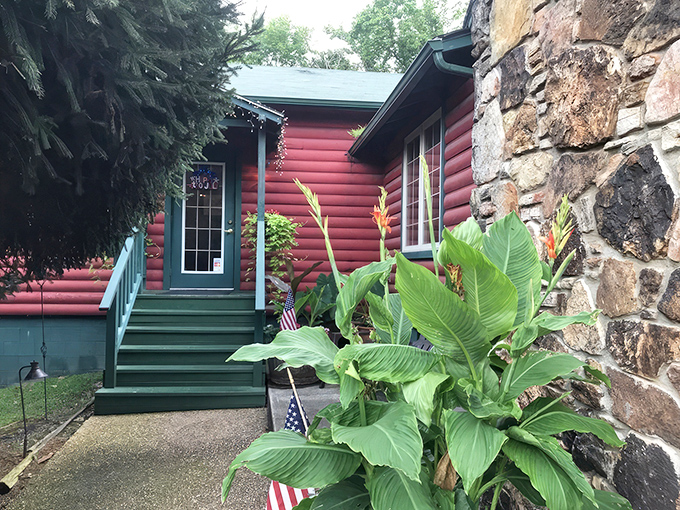 The red log cabin exterior with lush tropical plants says "frontier meets fine dining" before you even step inside.