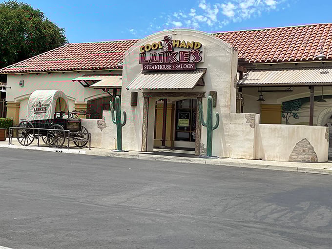 The Western-themed exterior of Cool Hand Luke's beckons with its iconic cactus sentinels and vintage wagon&mdash;like stepping onto a movie set where dinner is the star attraction.