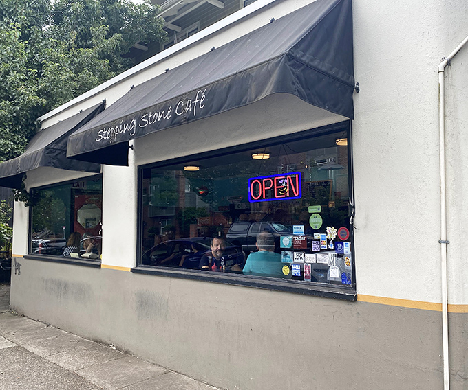 The unassuming storefront of Stepping Stone Caf&eacute;, with its simple black awning and neon "OPEN" sign, promises zero pretension and maximum flavor.