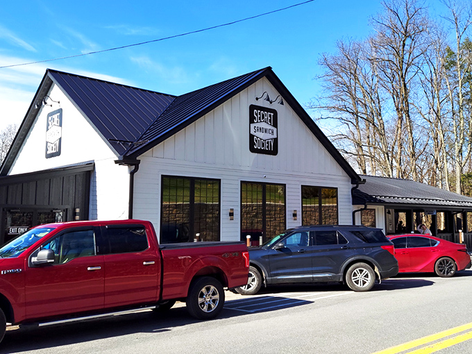 The charming white farmhouse exterior of Secret Sandwich Society stands like a beacon of hope for hungry travelers. Sandwich salvation awaits inside.