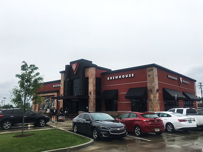 The bold red exterior of BJ's stands like a beacon for hungry travelers, promising craft brews and comfort food within those stone-accented walls.