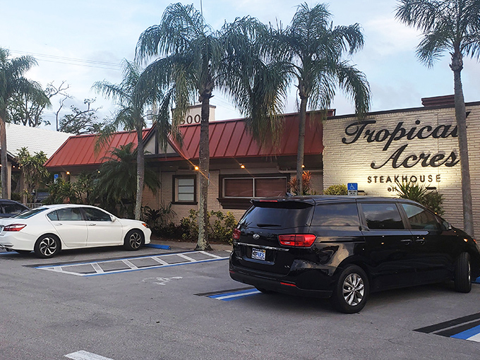 The unassuming exterior of Tropical Acres Steakhouse, where palm trees stand guard over Florida's best-kept carnivorous secret since 1949.