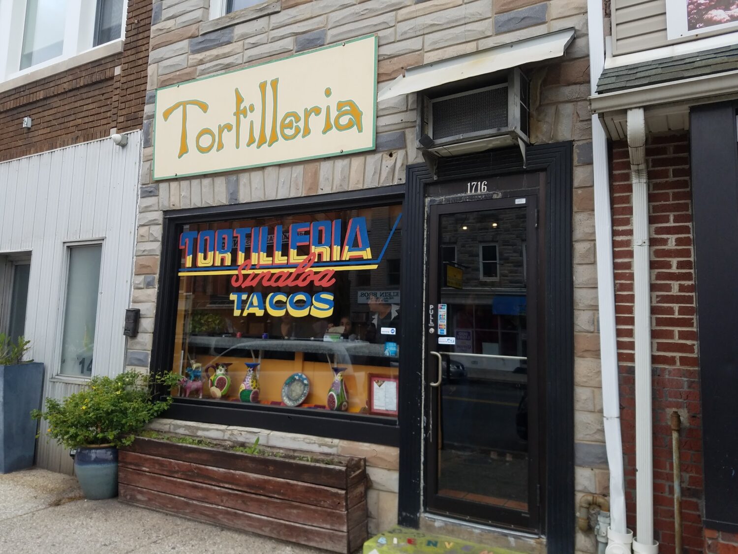 The storefront announces itself with vibrant blue, red, and yellow lettering that seems to say, "Yes, this is the real deal." Colorful ceramic pitchers in the window hint at the authenticity waiting inside.